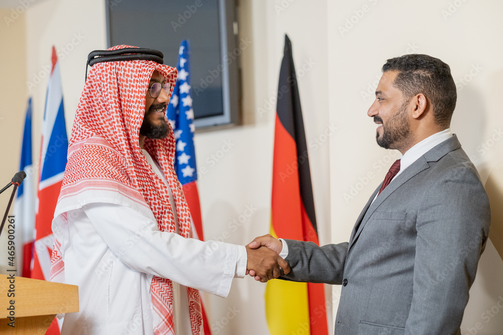 Smiling Middle Eastern politicians making handshake in conference room ...