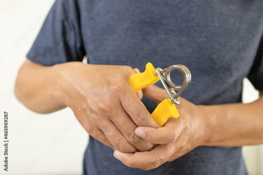 Hands of male patient is doing palm or wrist exercise with spring hand ...