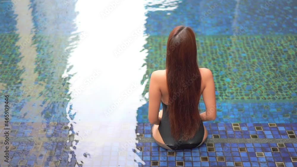 Stockvideon Back view of the fit Asian woman in black swimsuit sitting ...