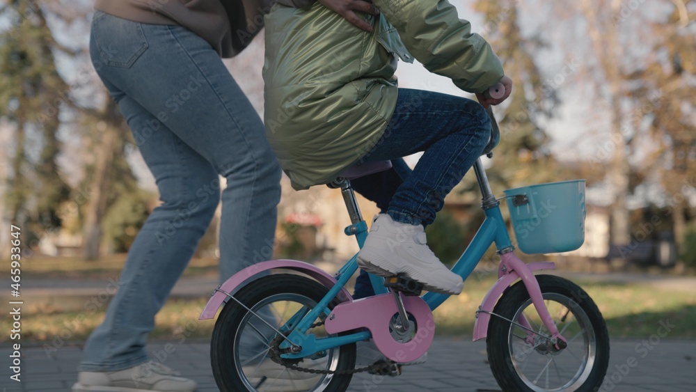 little kid learns to ride two-wheeled bike, child plays with his mother ...