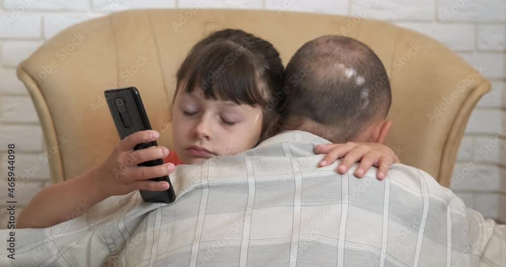 Cute daughter with phone with dad. A child embrace her father with a ...