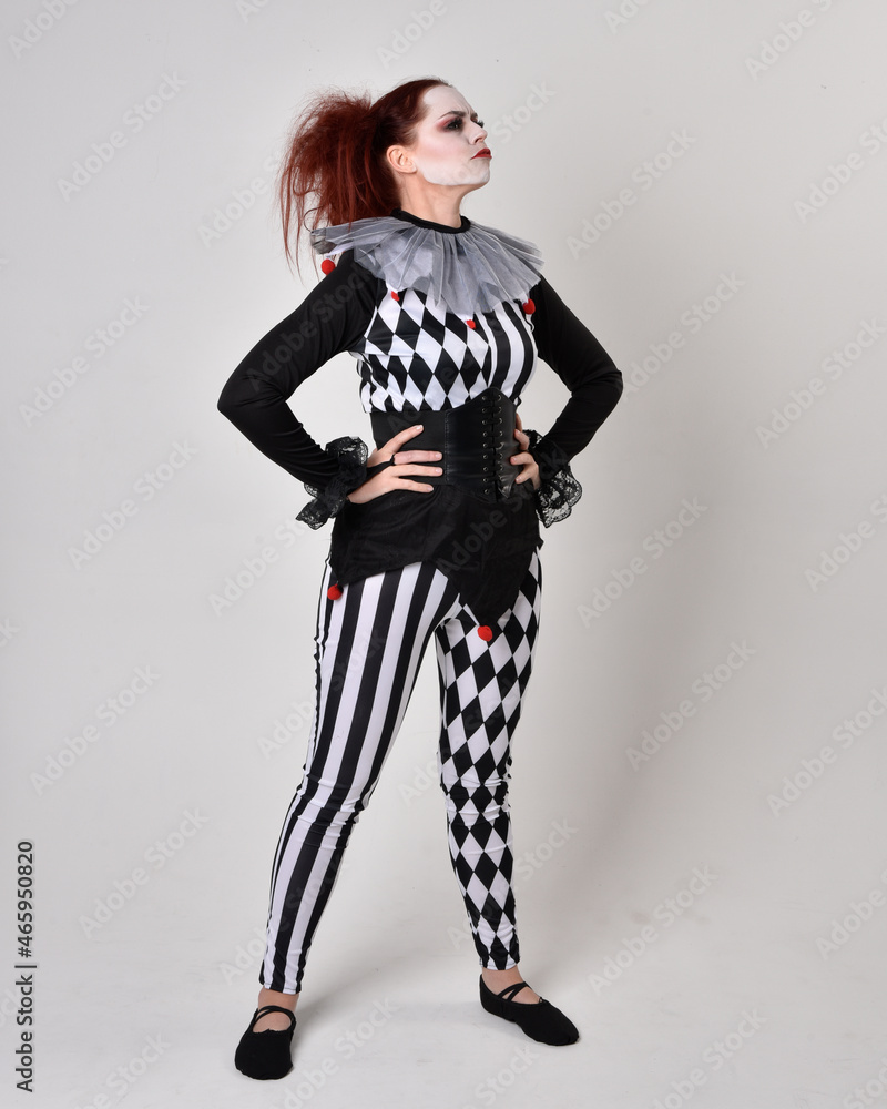 Full length portrait of red haired girl wearing a black and white clown ...