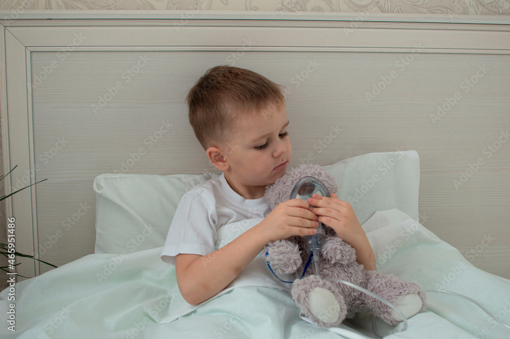 Sick child is sick at home, lying in bed with teddy bear. Does the ...