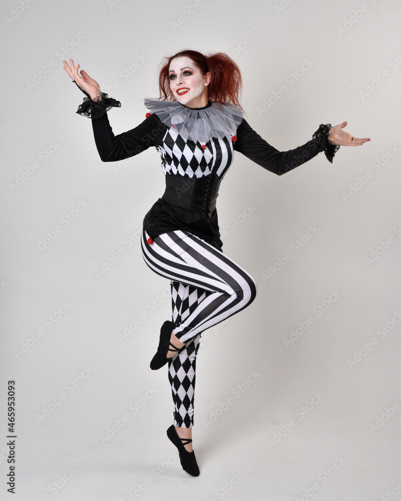 Full length portrait of red haired girl wearing a black and white clown ...