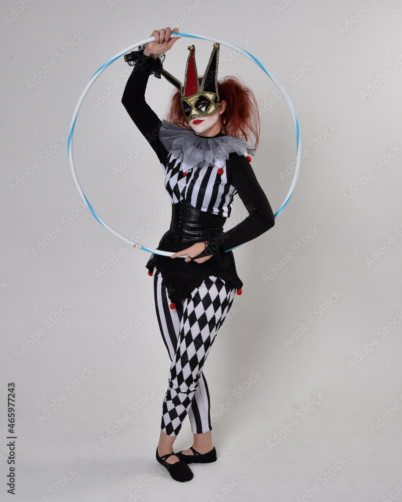 Full length portrait of red haired girl wearing a black and white clown ...