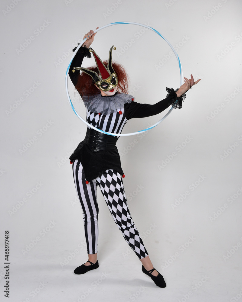 Full length portrait of red haired girl wearing a black and white clown ...