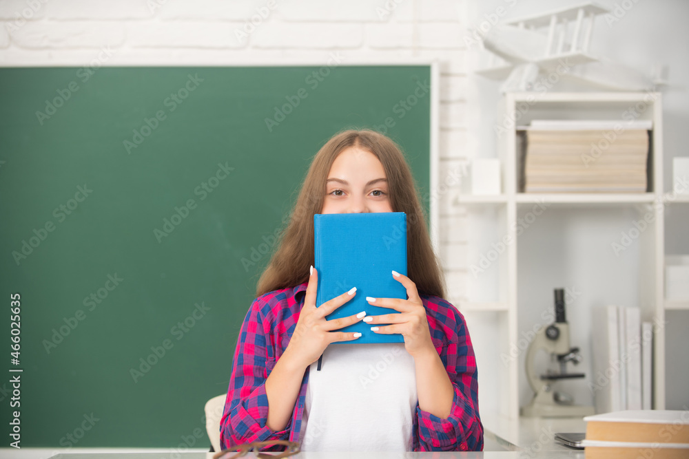 child hiding behind book at school on blackboard background, knowledge ...