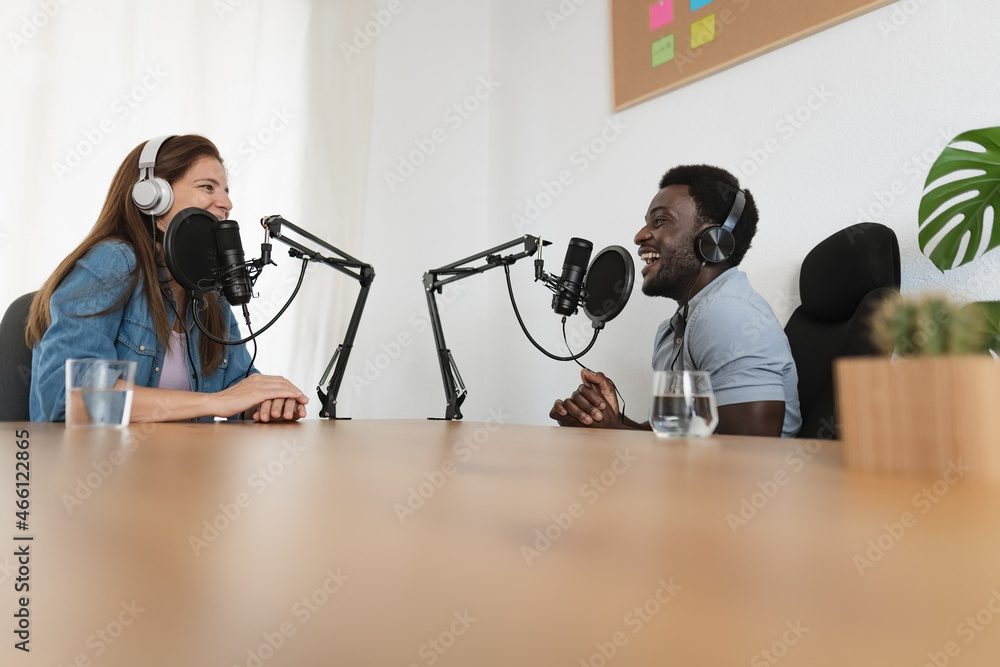 Multiracial people recording a podcast using microphone and headphones ...