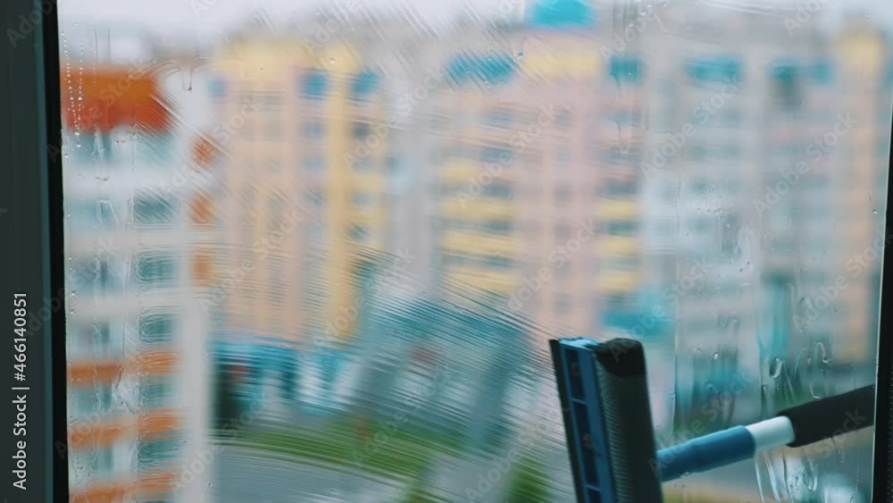 Washing a window in the city. Wet window is cleaning with special brush ...