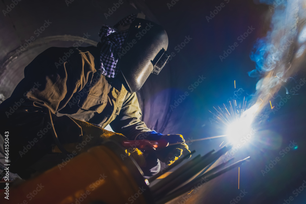 MMA welding. A welder welds large diameter pipes with manual electric ...