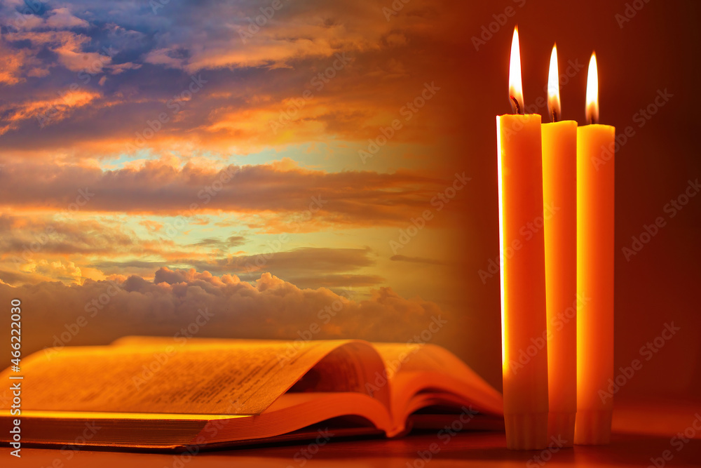 Candles and an open book as a symbol of religion. holy book on ...