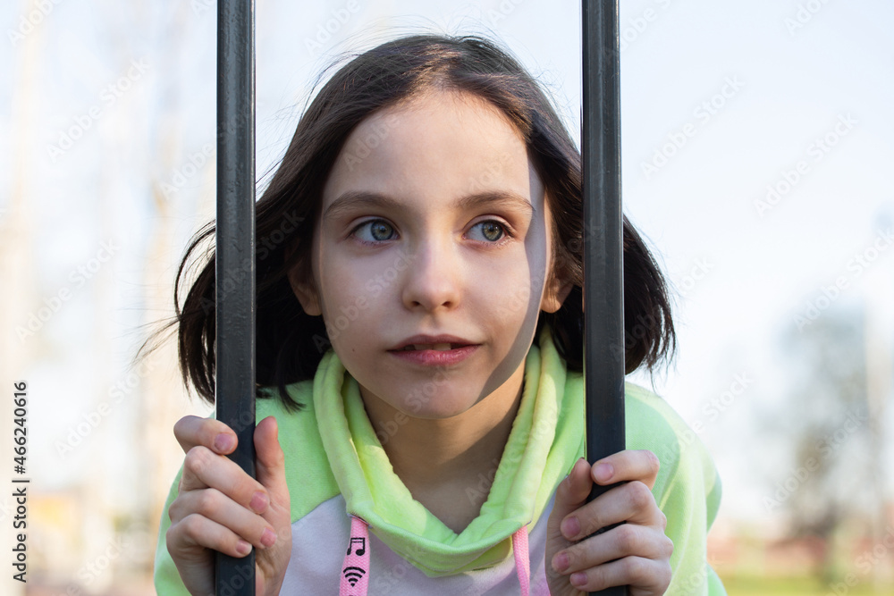 Crop close up portrait of serious sad little girl girl behind bars look ...