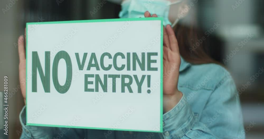 Woman wearing face mask attaching sign on the glass in pandemic time ...