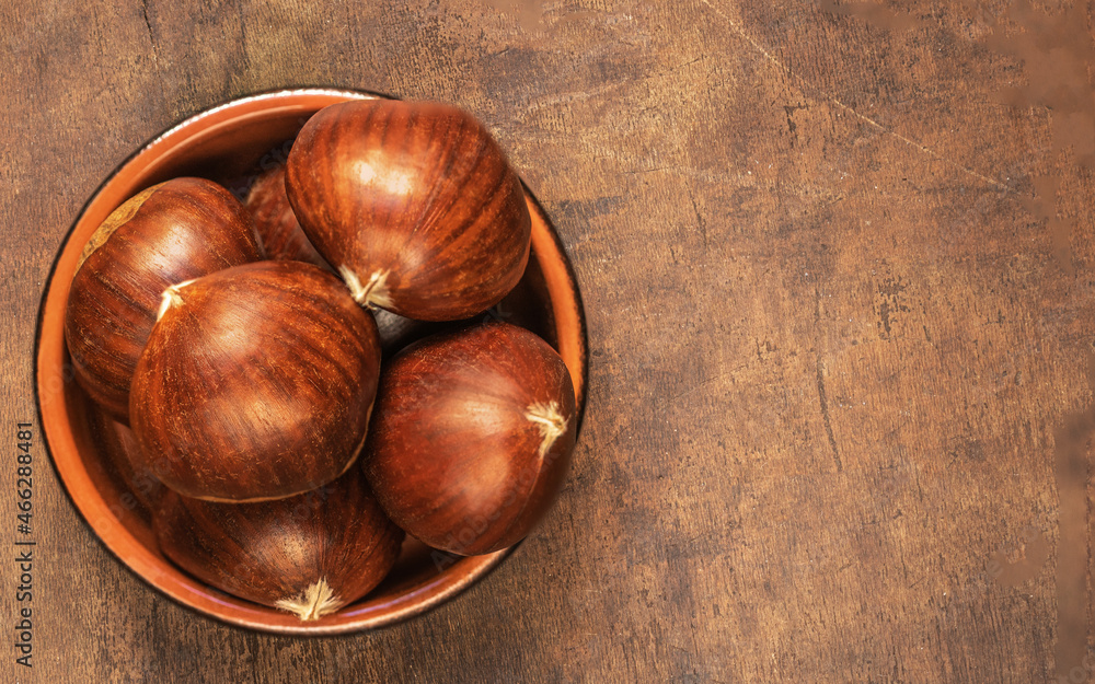 Sweet chestnuts on old rustic wooden table with plenty of copy space ...