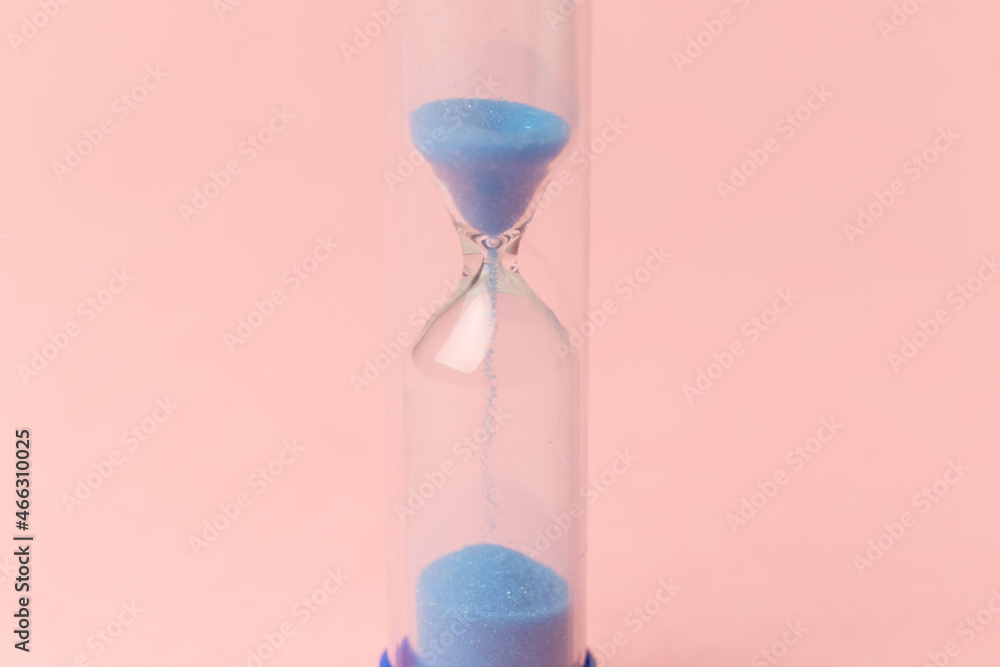 Modern blue Hourglass on pink background. Sand trickling through the ...