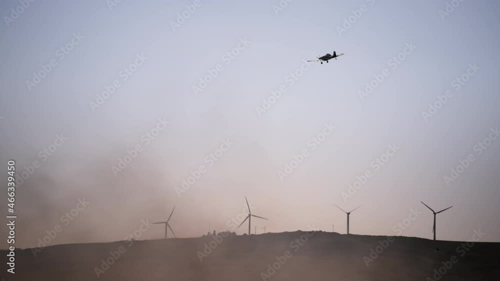 Small firefighting airplane flying above wind turbines next to the big ...