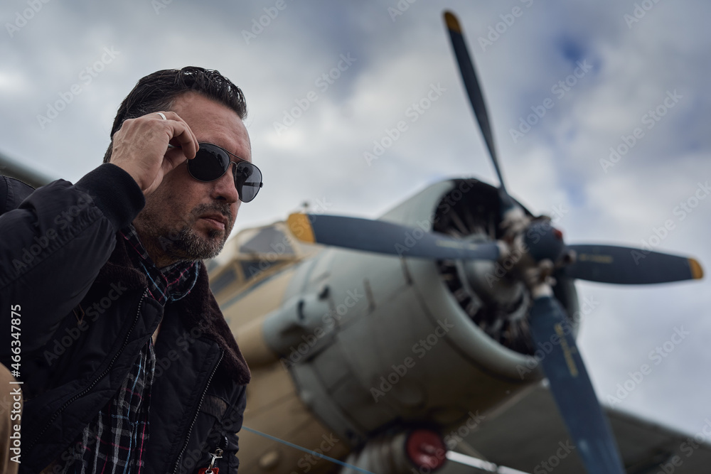 Oldschool pilot in the bomber jacket posing near the aircraft, aviator ...