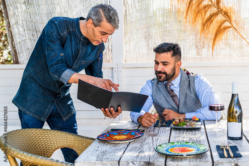 Male chef showing menu to customer at restaurant Stock Photo | Adobe Stock