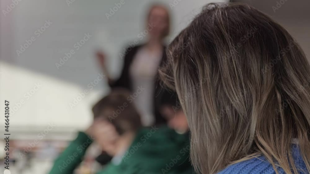 Back view of a woman in a lecture hall, listening to a professor giving ...