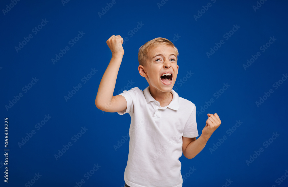 White blonde boy wearing shirt screaming while making winner gesture ...