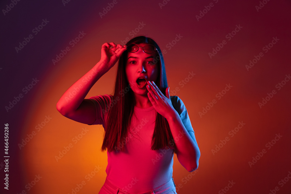 Surprised, shocked girl isolated on dark studio background in neon ...