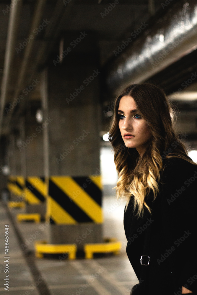 Attractive young brown-haired woman posing in an underground parking ...