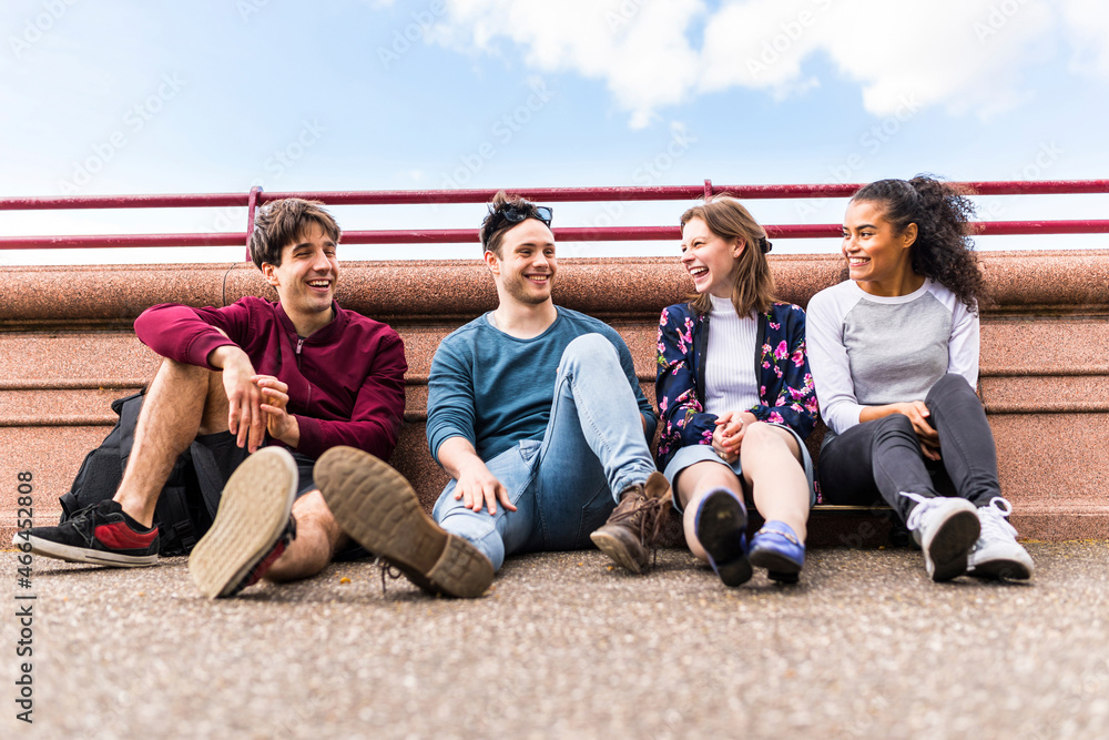 Happy friends talking to each other in front of wall Stock Photo ...
