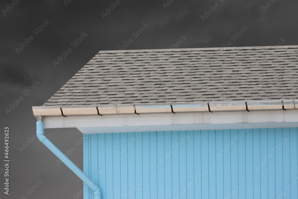 stainless rain gutter with roof shingle of house with dark cloud ...