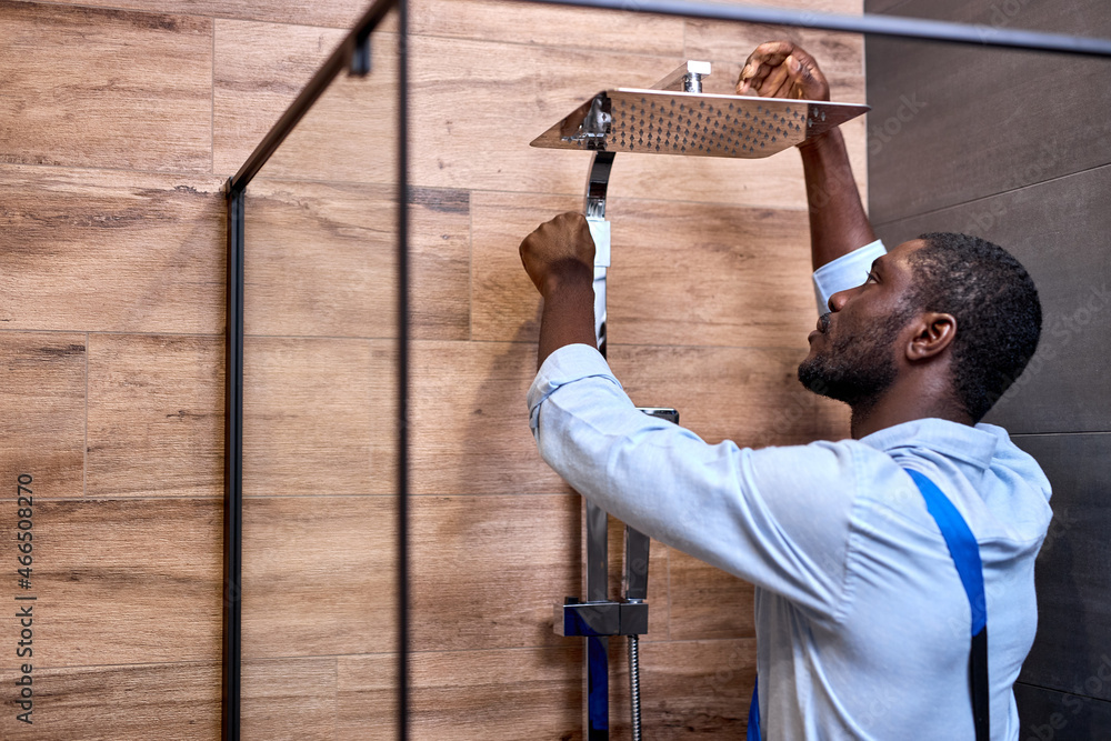 Afro american Professional handyman working in shower bath indoors ...