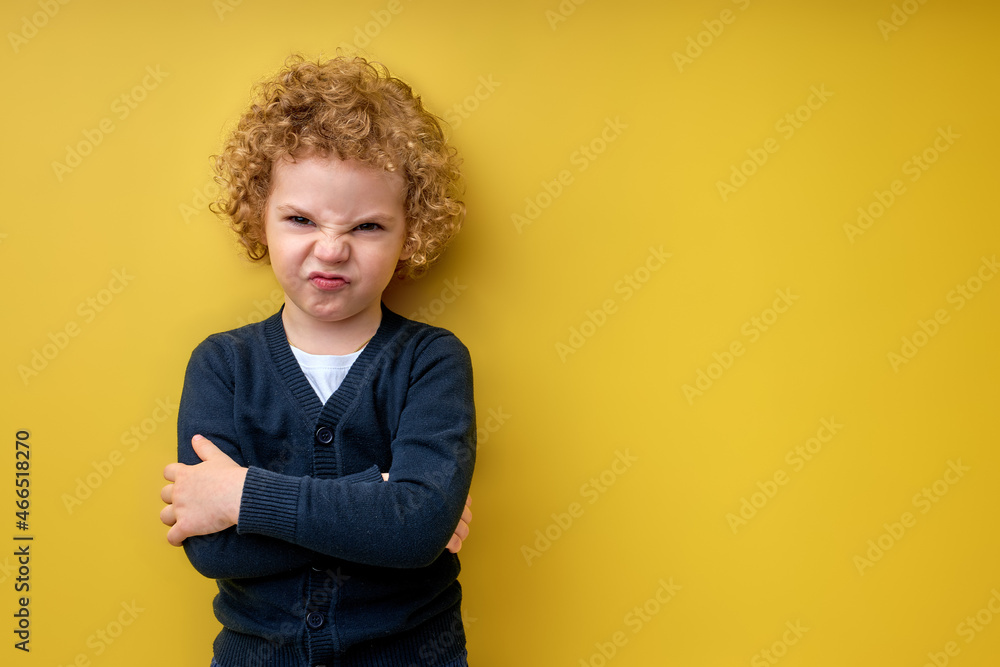 Curly offended child boy with arms folded posing at camera, isolated on ...