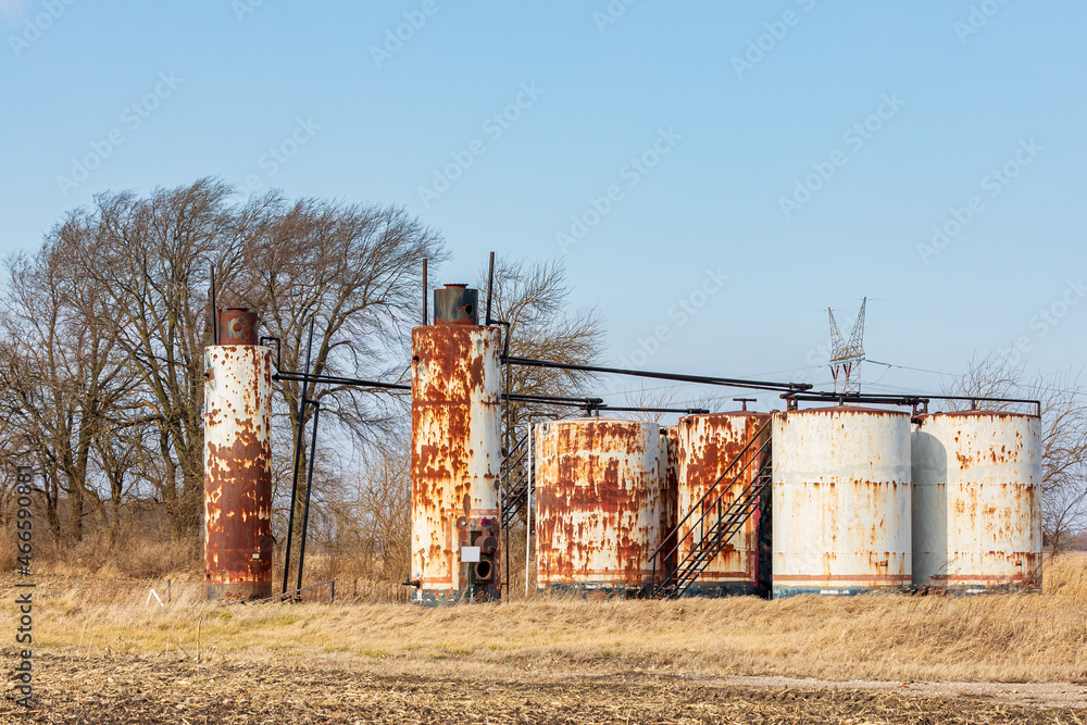 Old oil well storage tanks in farm field. Oil well abandonment ...