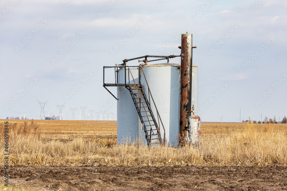 Old oil well storage tanks in farm field. Oil well abandonment ...