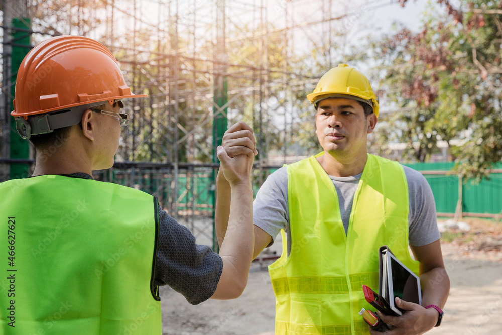 Builders greeting each other with handshake on construction site ...