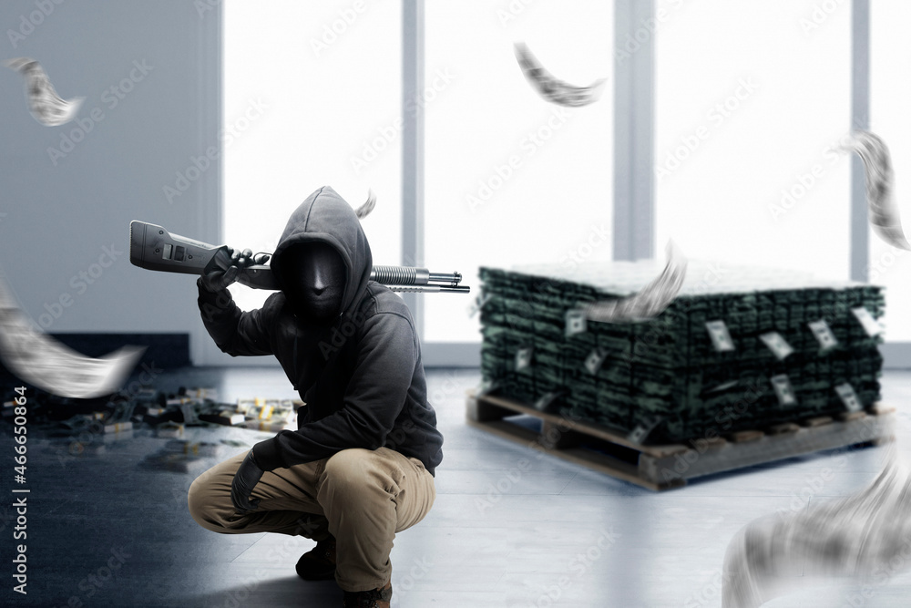 Criminal man in a hidden mask sitting and holding the shotgun while ...