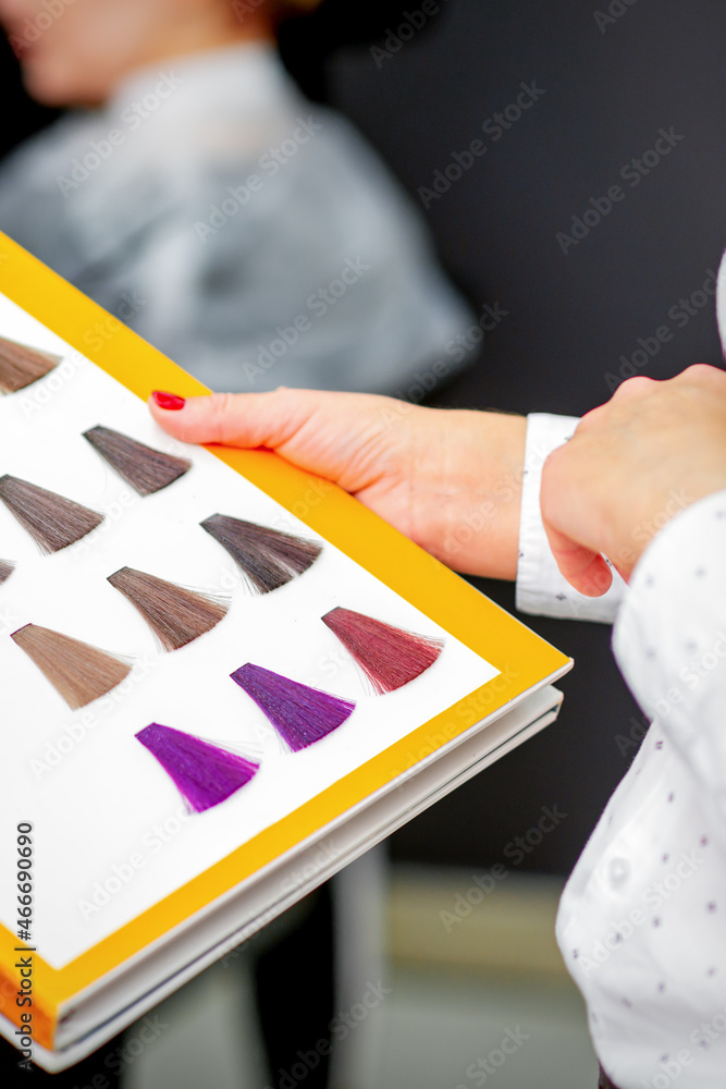 Young caucasian woman choosing a color from the hair color chart in a ...