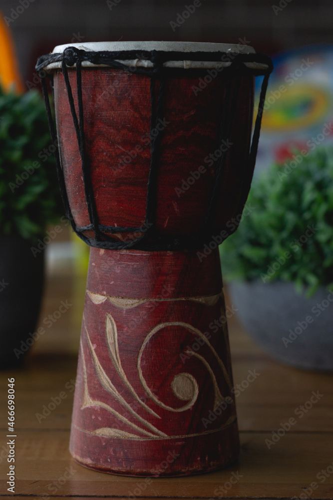 Djembe music instrument standing on wooden floor. Indigenous design ...