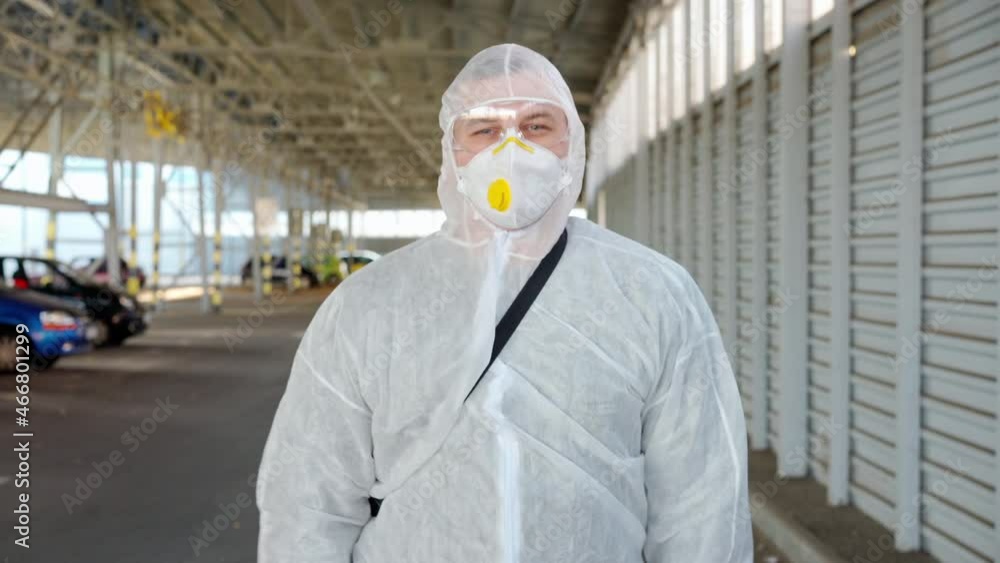 Man dressed protective overalls walk parking. Disinfectant walking with ...