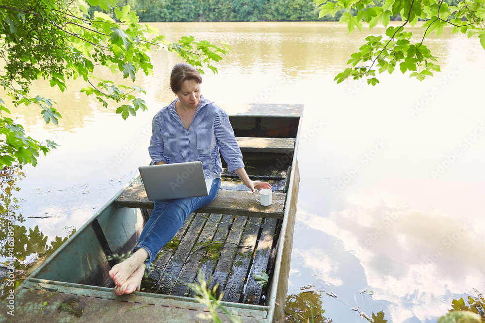 Freelance woman working on laptop pc in a boat Stock Photo | Adobe Stock