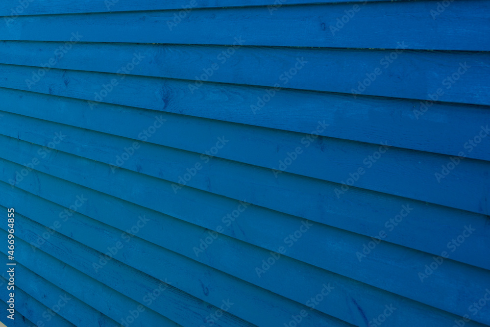 The exterior wall of a bright blue building. The textured wood is made ...