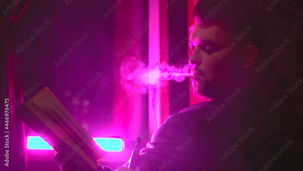 Video Stock Portrait of a young caucasian man reading a book smoking a ...