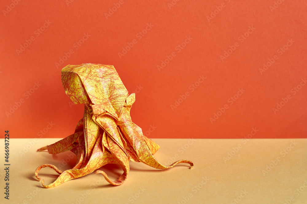 Origami octopus model on a yellow and orange background. Origami figure ...