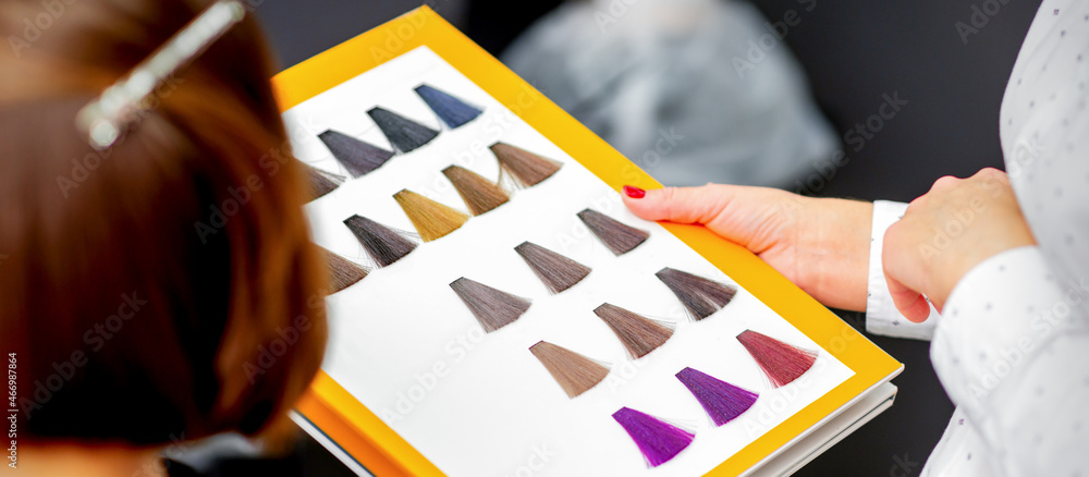 Young caucasian woman choosing a color from the hair color chart in a ...