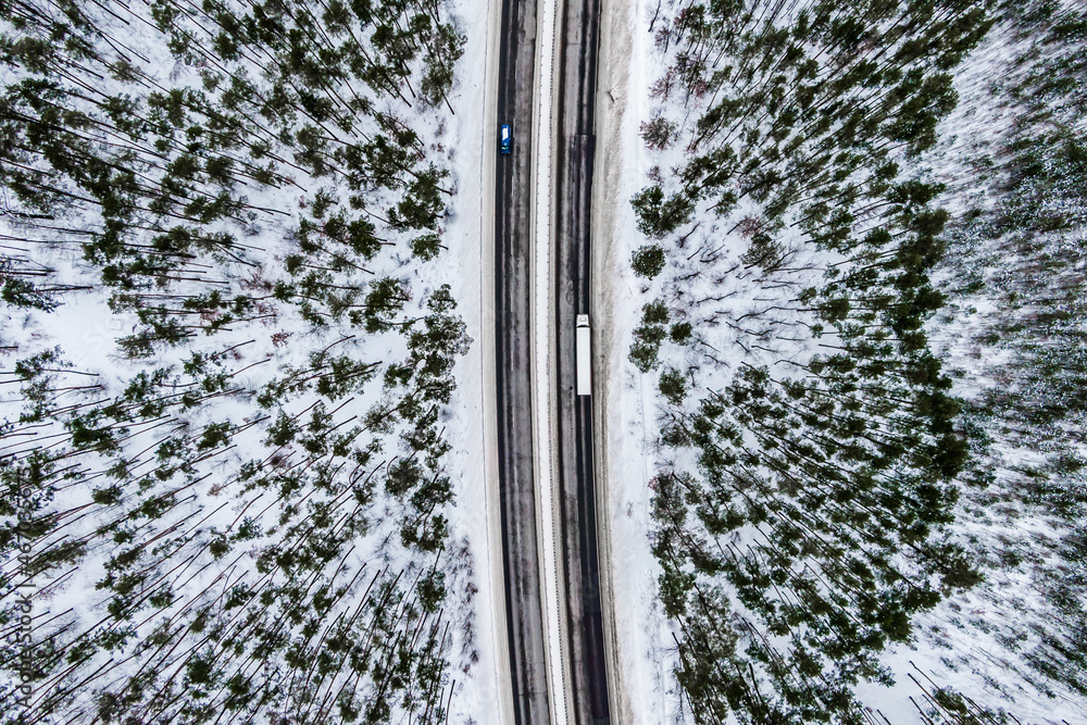 Aerial view of snow covered road in winter forest white truck driving ...