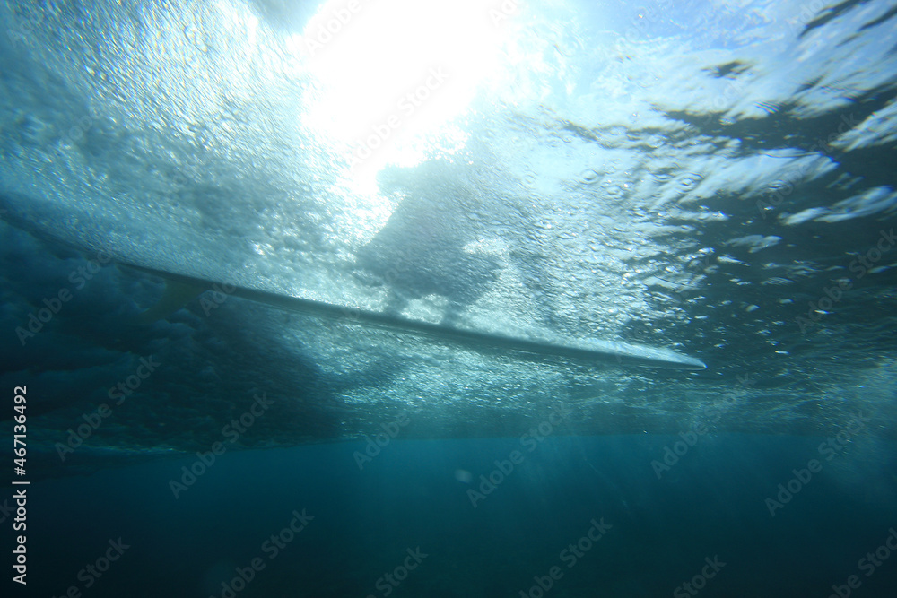surfer riding a surfboard on a wave photographed from underwater with ...