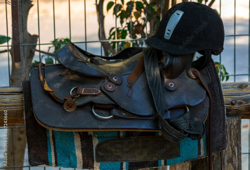 Old saddle on fence, blanket and other tack. Sport leather saddle ...