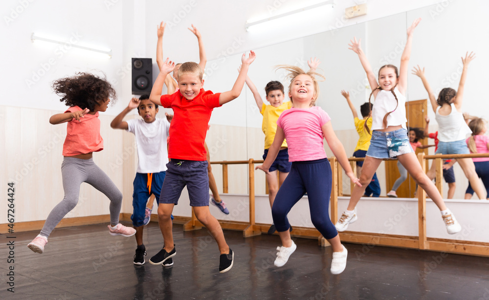 Happy kids of different nationalities and ages jumping during class in ...