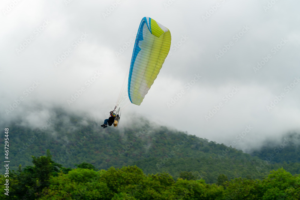 The sportsman on a paramotor gliding and flying in the air with ...