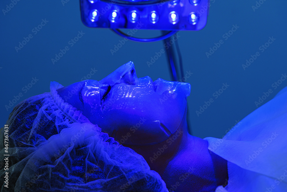 Young woman having blue LED light facial therapy treatment in beauty ...