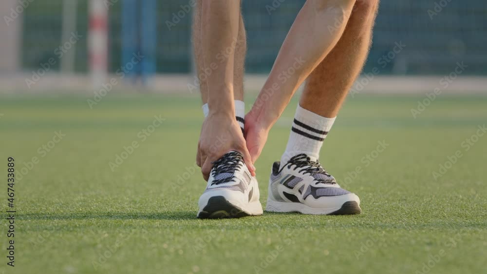 Close-up of strong male legs in white sneakers and socks on grass of ...