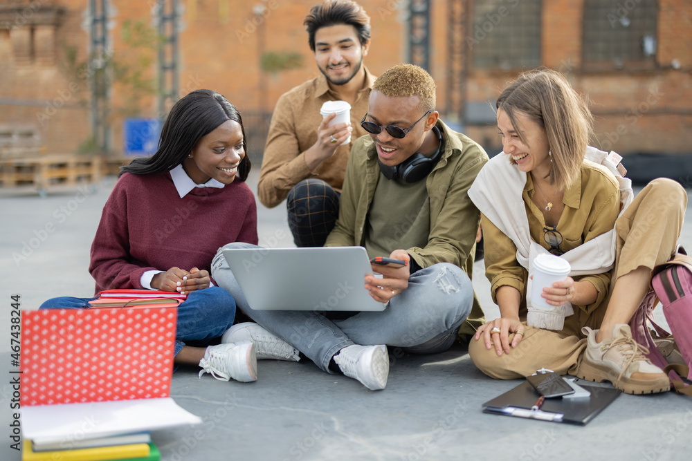 Multiracial students sitting and watching something on laptop computer ...